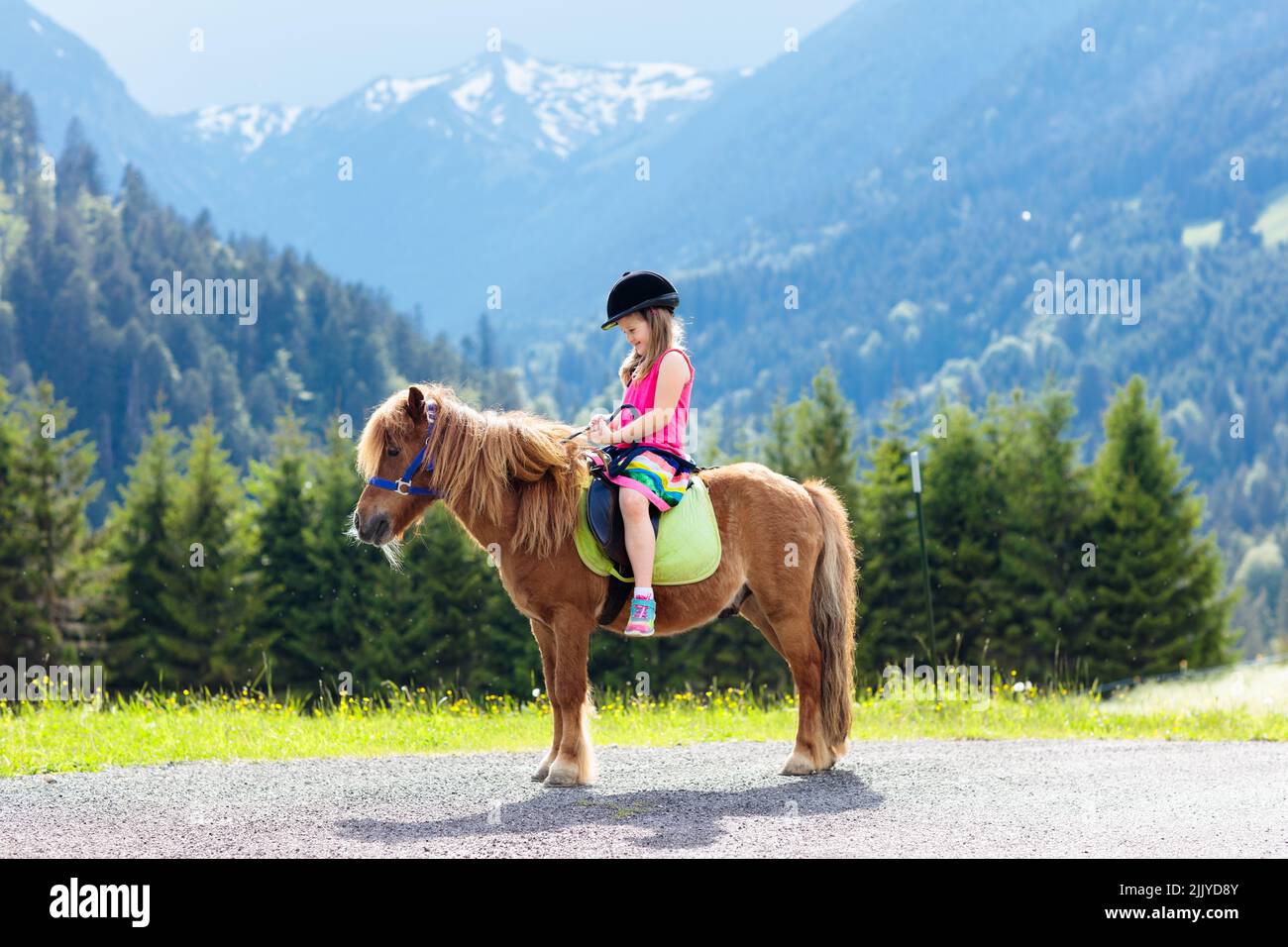 Kids riding pony in the Alps mountains. Family spring vacation on horse ...