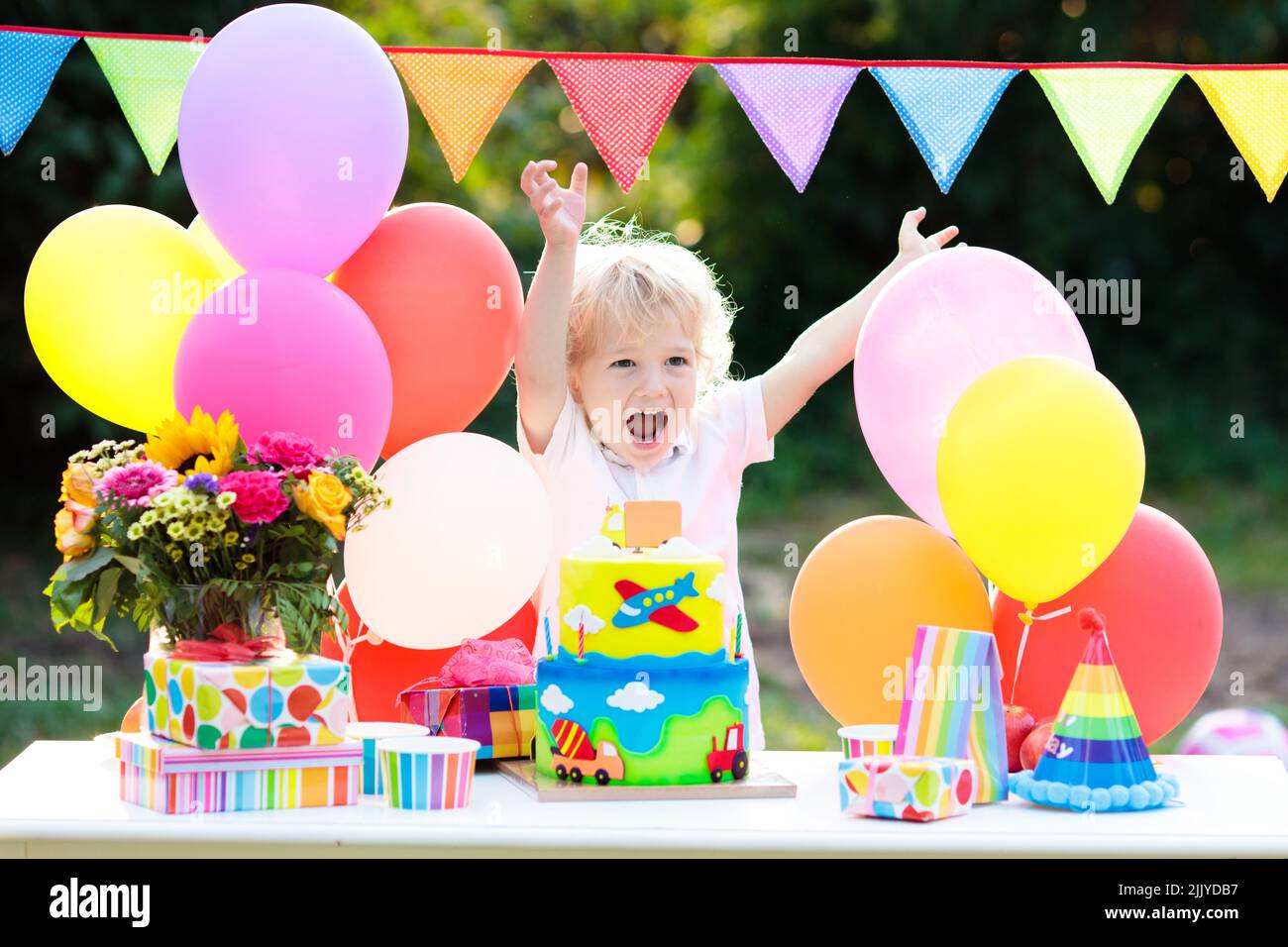 Kids birthday party. Child blowing out candles on colorful cake ...