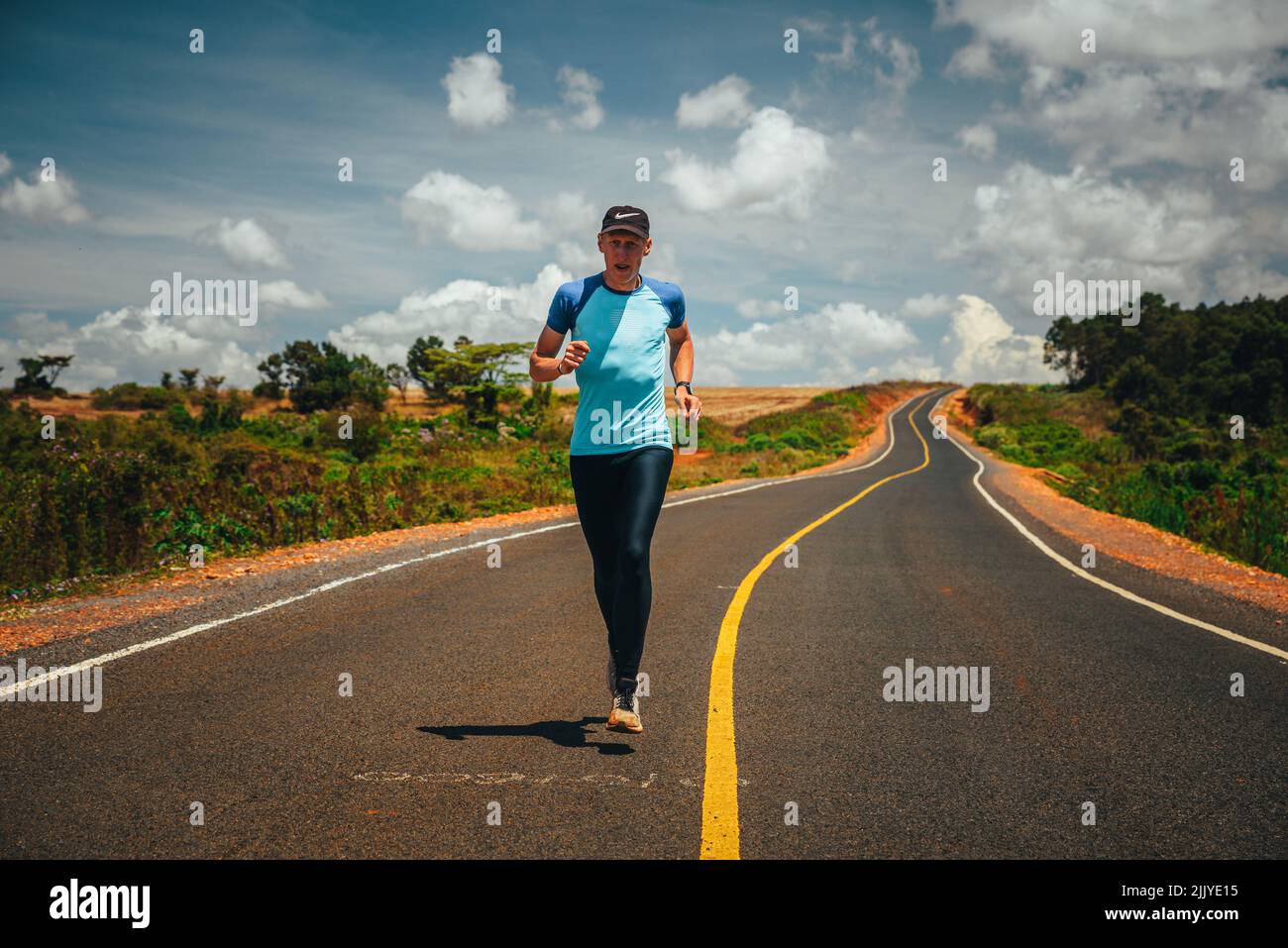 Endurance runner running on asphalt road in African nature. Marathon ...
