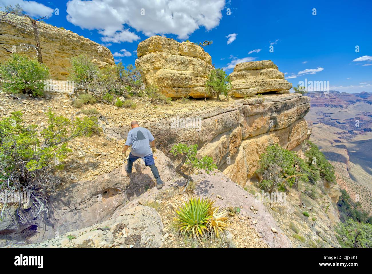 A hiker jumping across a crevice along a cliff west of Twin Views ...