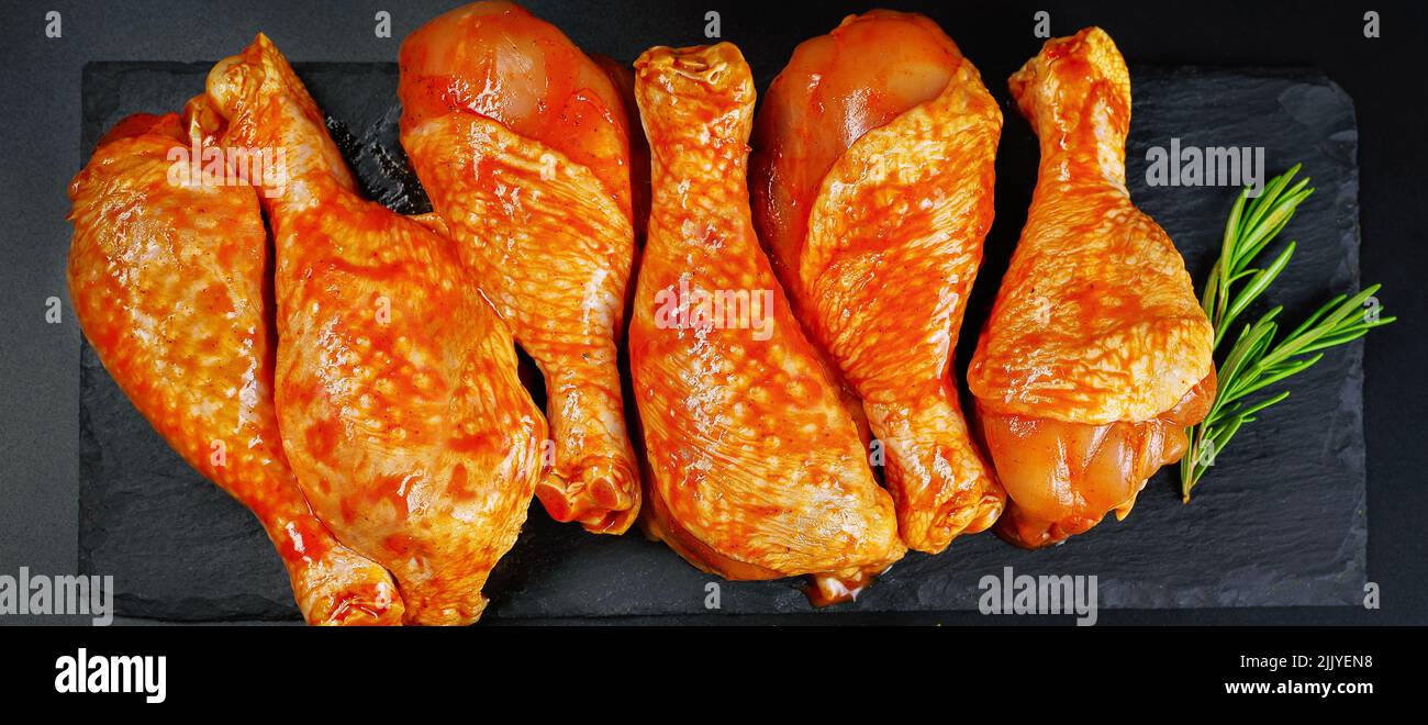 Barbeque marinated chicken dramsticks on a black cooking board on a ...