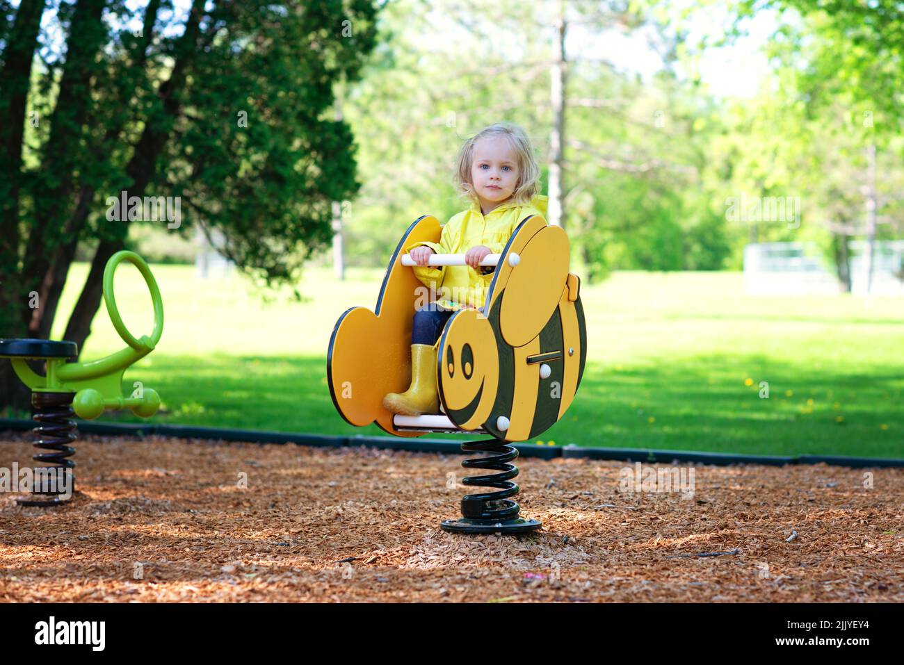 Little blond girl playing at the park on bee ride Stock Photo - Alamy
