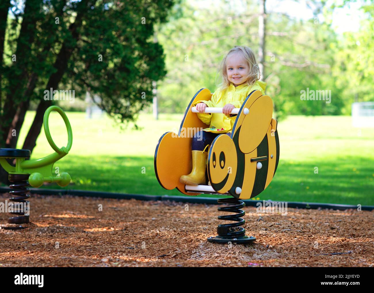 Little blond girl playing at the park on bee ride Stock Photo - Alamy
