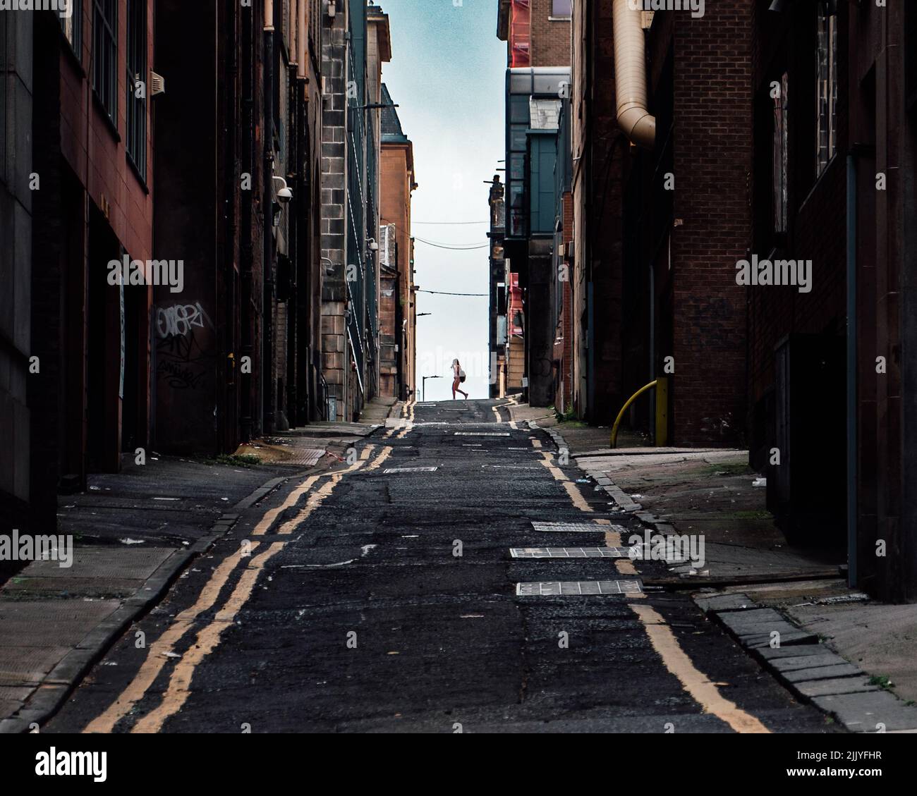 A girl from far crossing an empty street, between buildings Stock Photo ...
