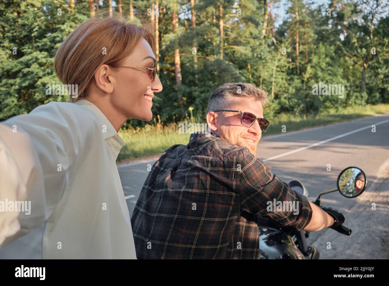 Middle age couple riding a motorcycle having fun and taking selfies ...