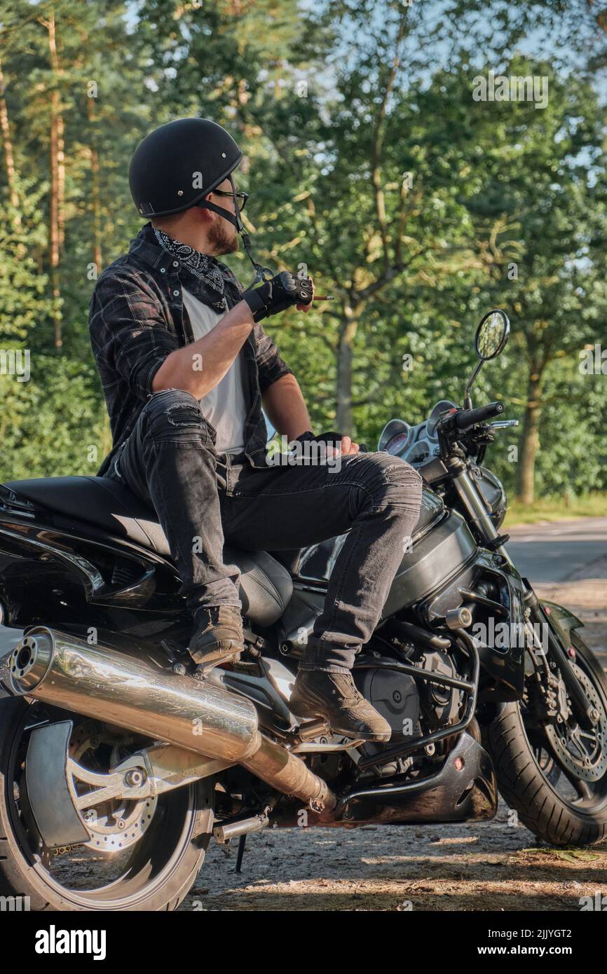Young male biker in helmet travels on a motorcycle alone, stopped and ...