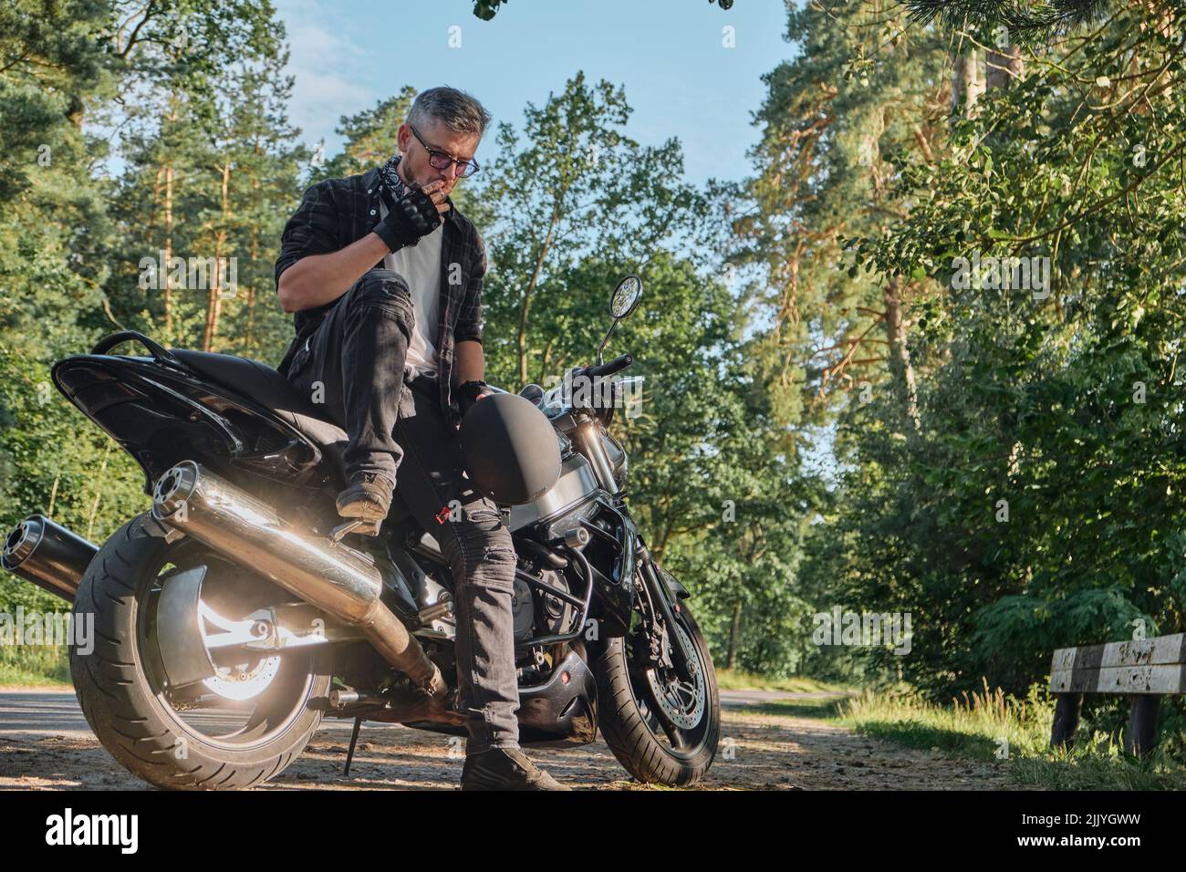 Young male biker travels on a motorcycle alone, stopped and smoking on ...