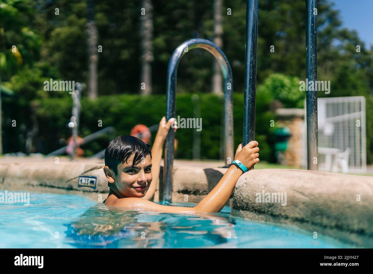 Teenage boy climbing out of pool by ladder Stock Photo - Alamy