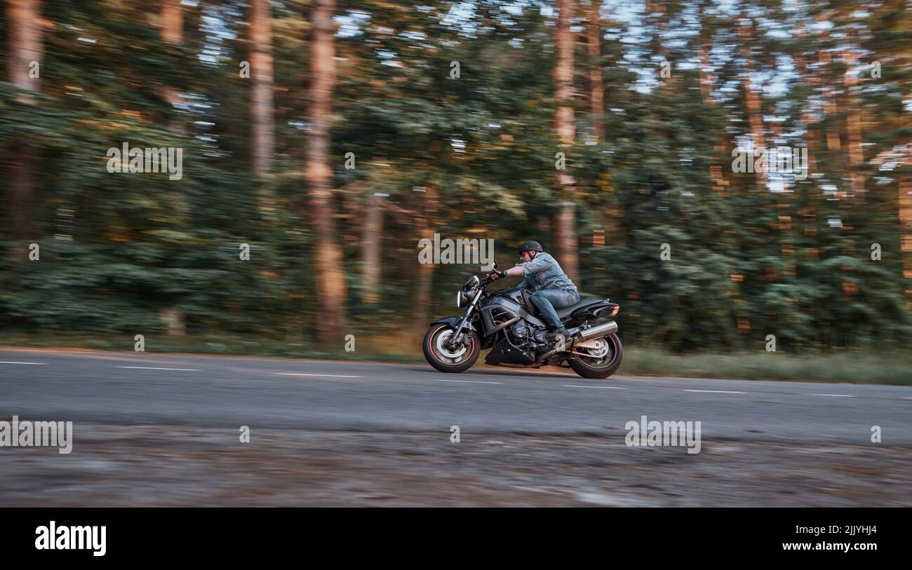 Blurred Motion A young man biker in a helmet quickly rides at high ...