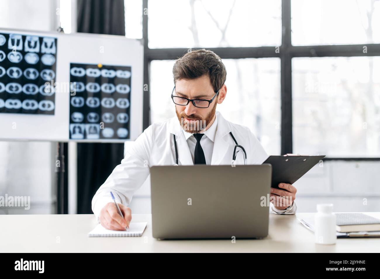 Professional male caucasian doctor, sitting at a desk in a medical ...