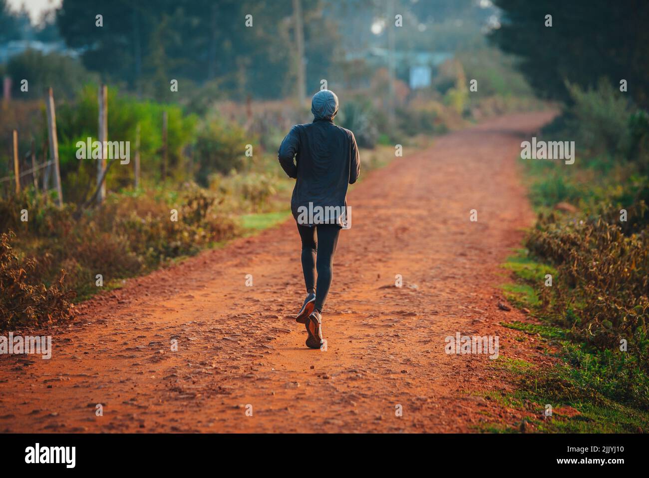 A lone runner trains in Kenya. A marathon runner runs on red soil in ...