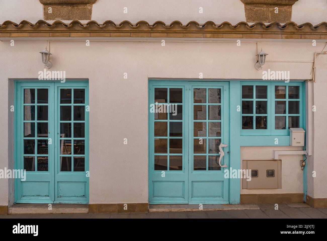 Exterior of a cafe building with teal blue doors and windows in Tossa ...