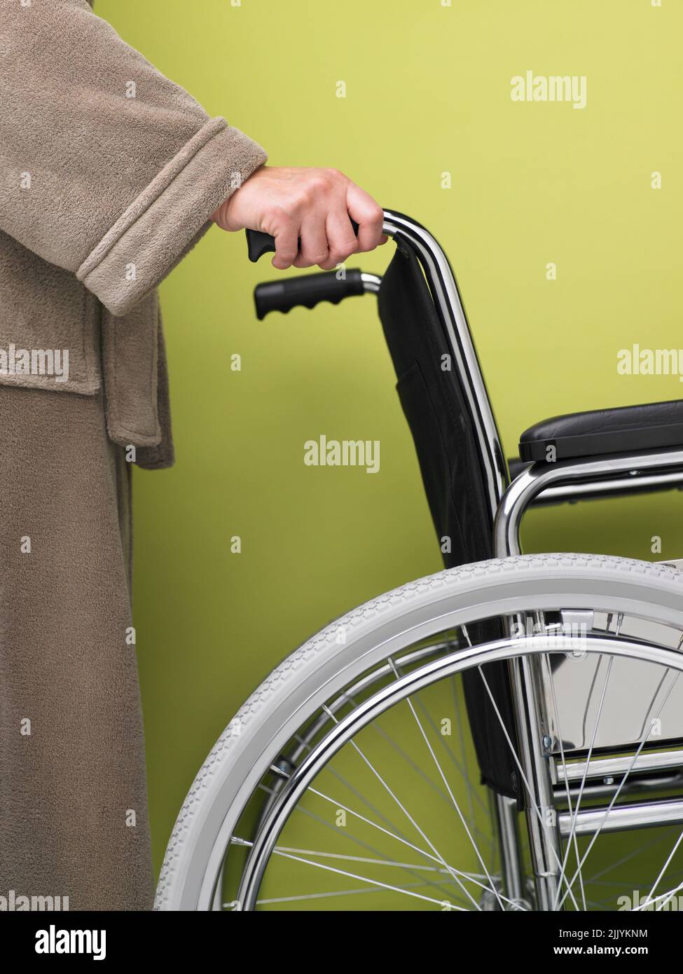 Close up of woman wearing robe holding on to wheelchair Stock Photo - Alamy