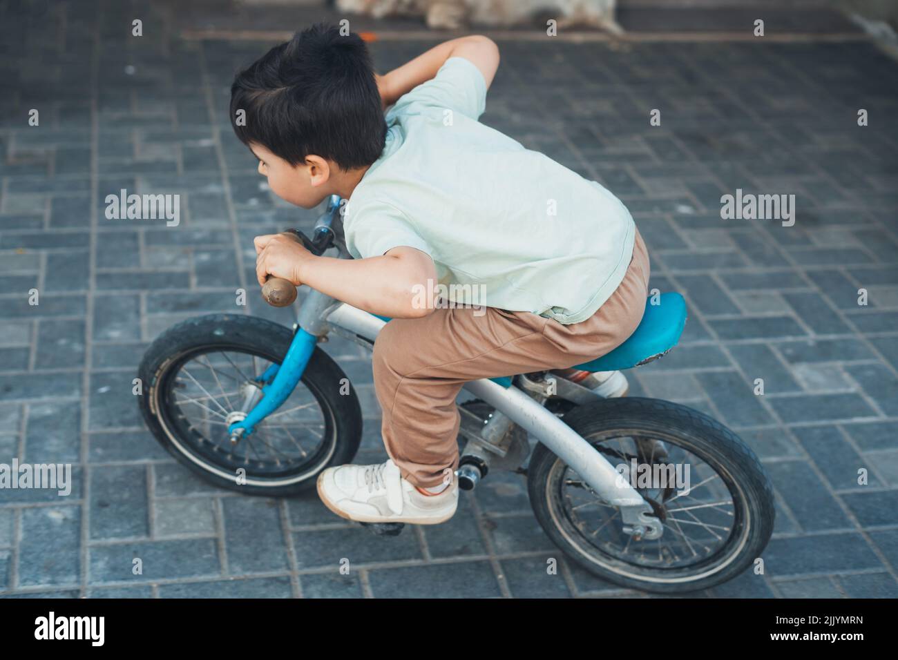 Caucasian boy playing with his bicycle in the yard of his house. Boy ...