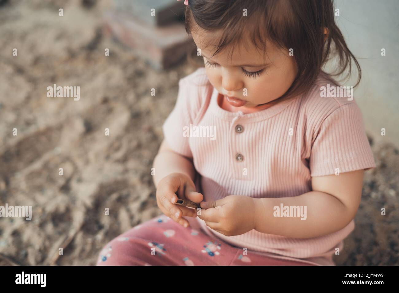Concentrated baby girl playing in the sand at the playground. Baby ...
