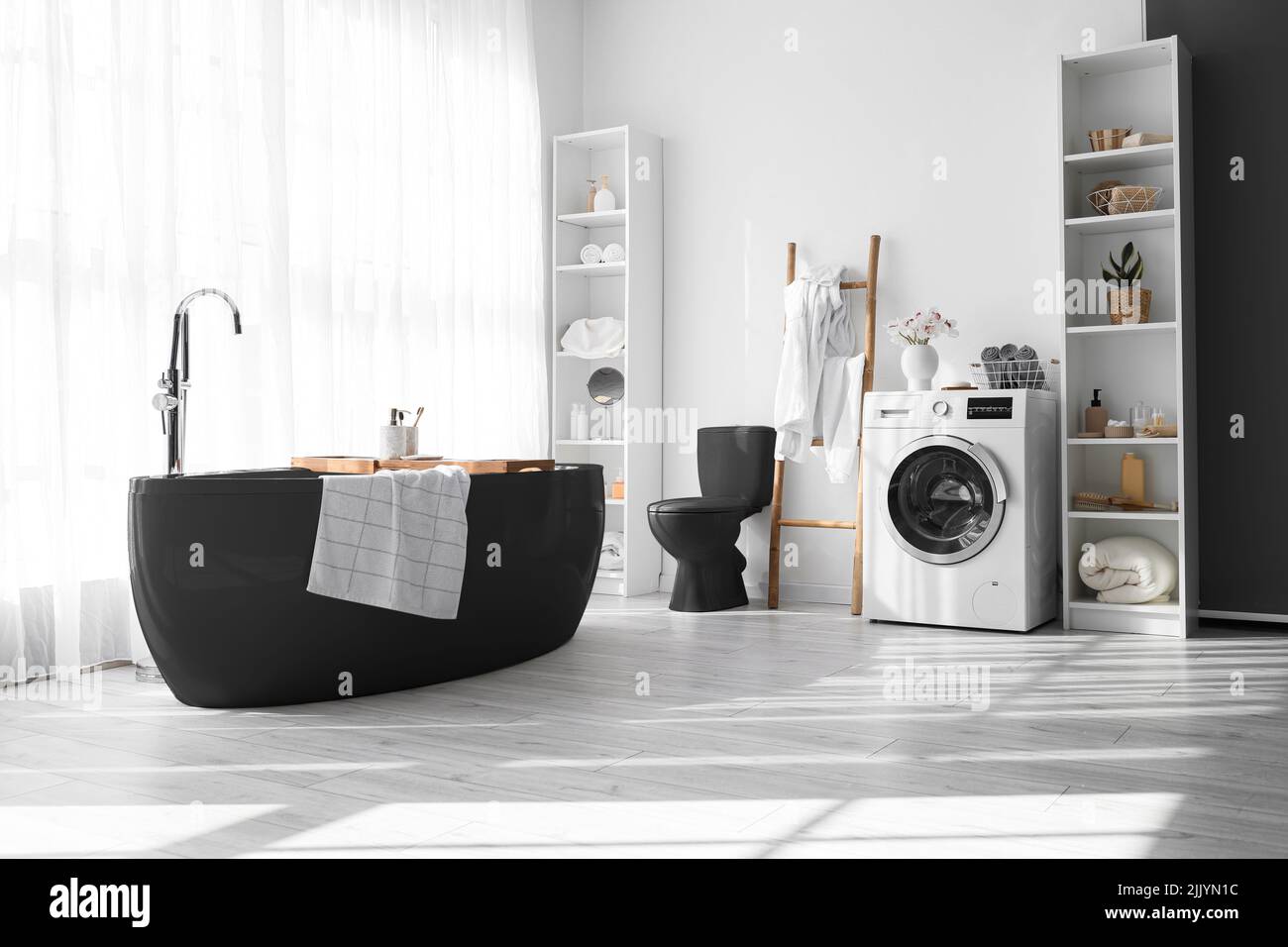 Stylish interior of light bathroom with bathtub, washing machine ...
