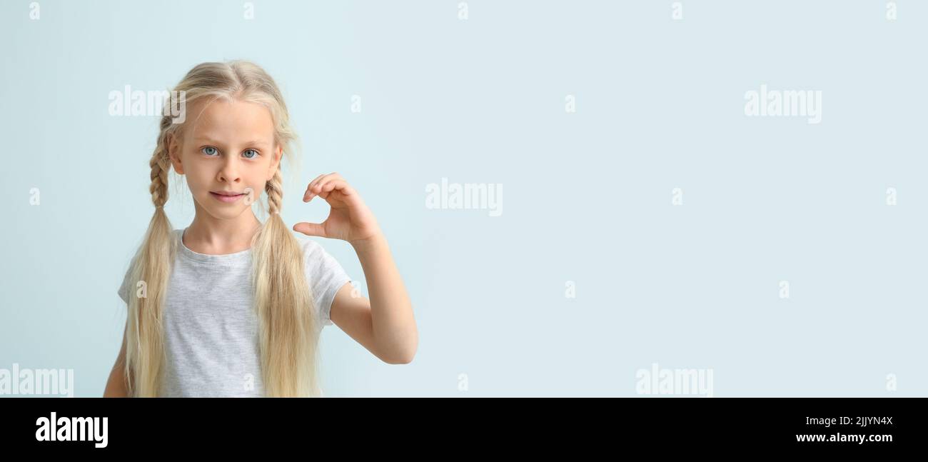 Little deaf mute girl using sign language on light background with ...