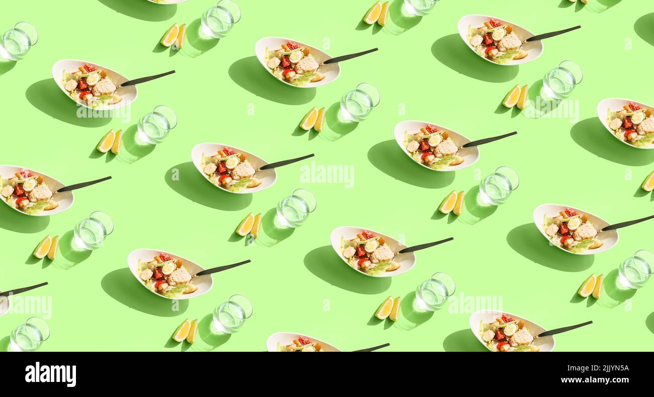 Many bowls of Caesar salad and glasses of water on green background ...