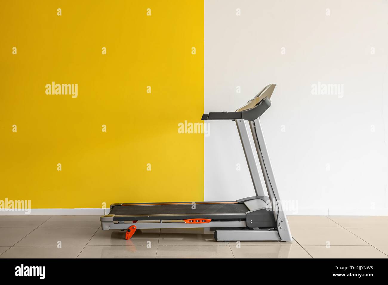 Modern treadmill near yellow and white wall Stock Photo - Alamy