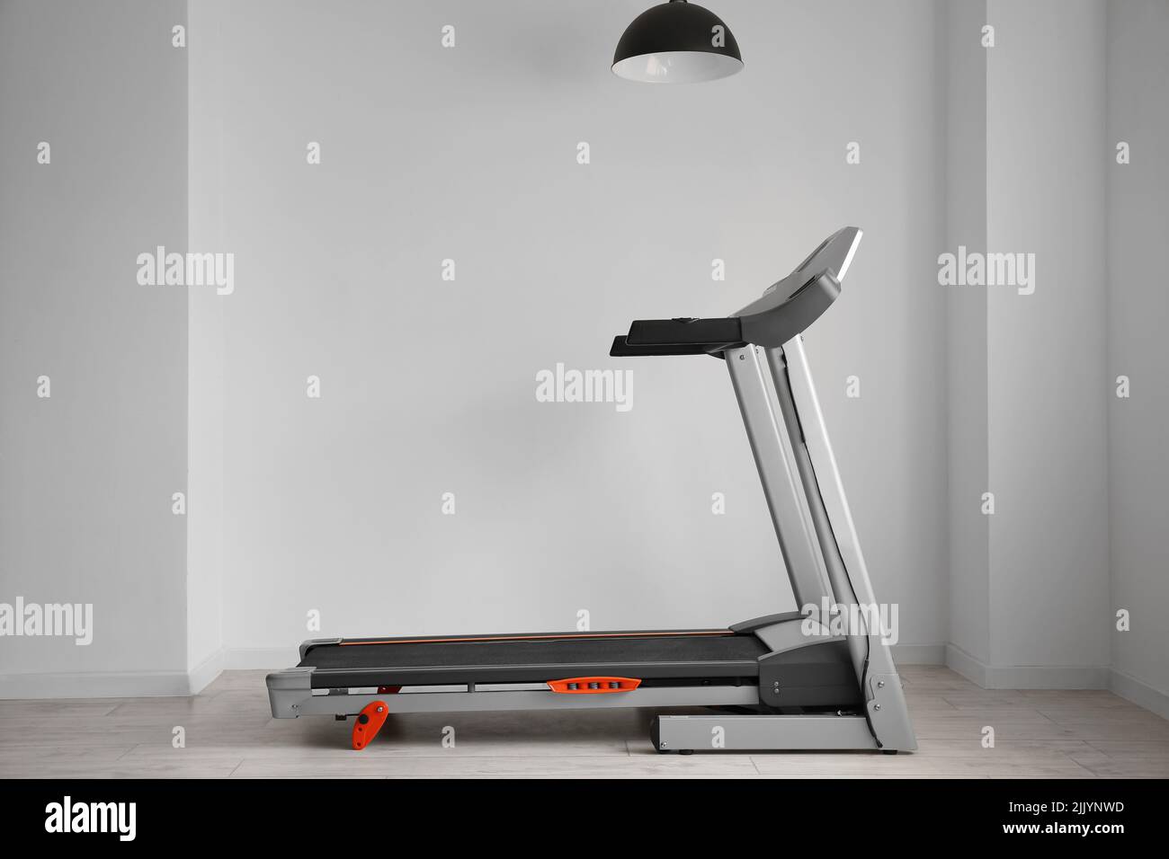 Modern treadmill and hanging lamp in light room Stock Photo - Alamy