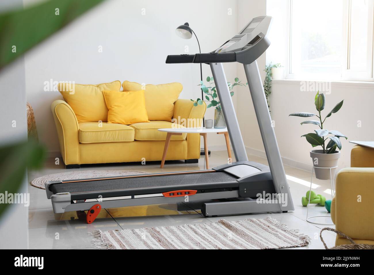 Interior of light living room with treadmill and yellow sofa Stock ...