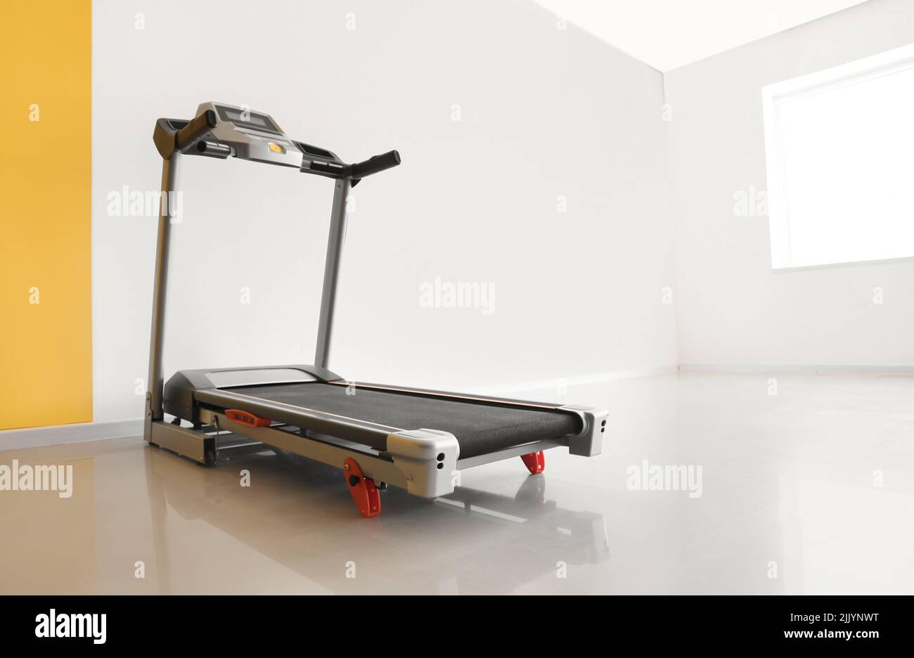 Modern treadmill near yellow and white wall Stock Photo - Alamy