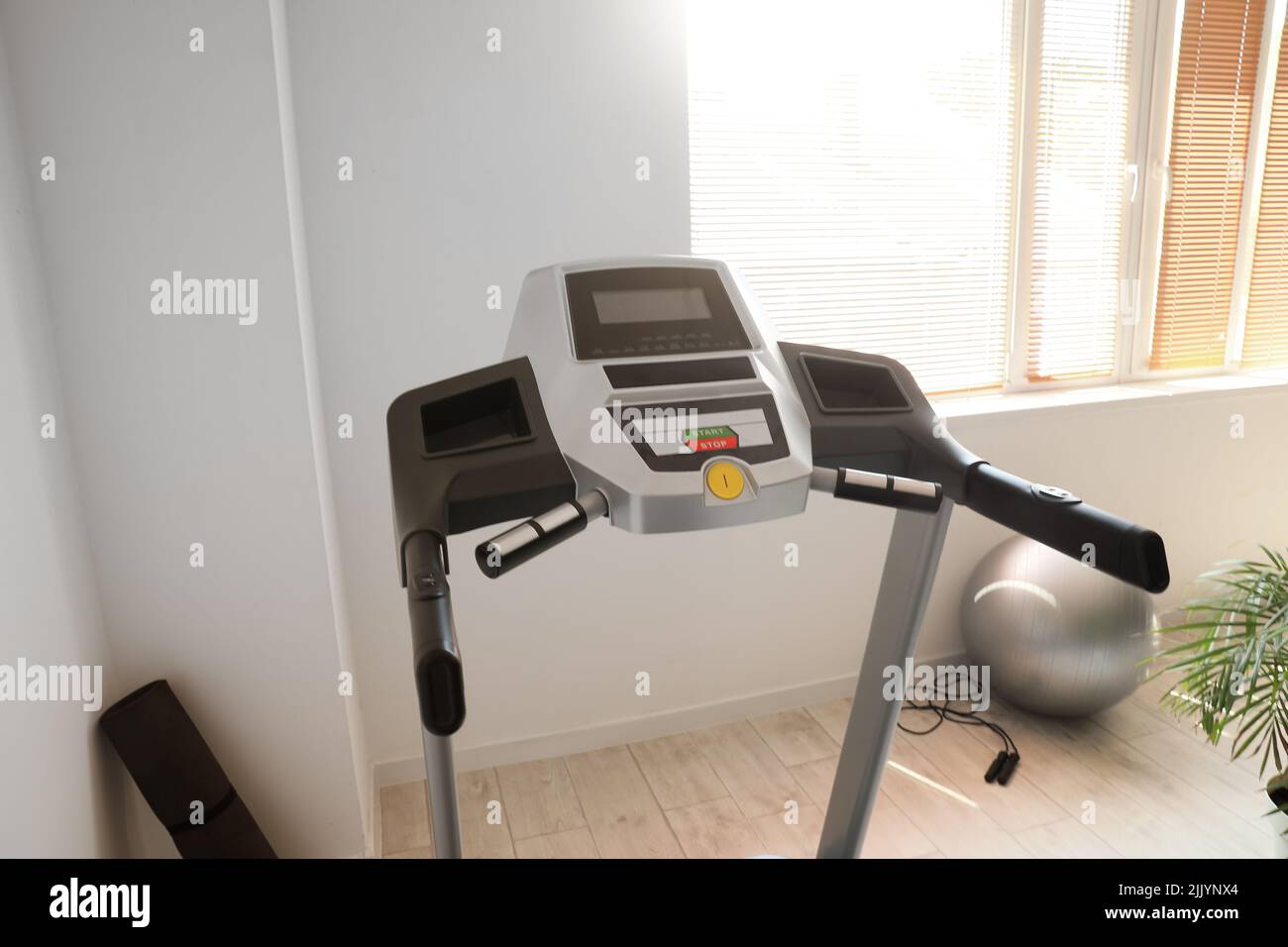 Modern treadmill near window in gym, closeup Stock Photo - Alamy