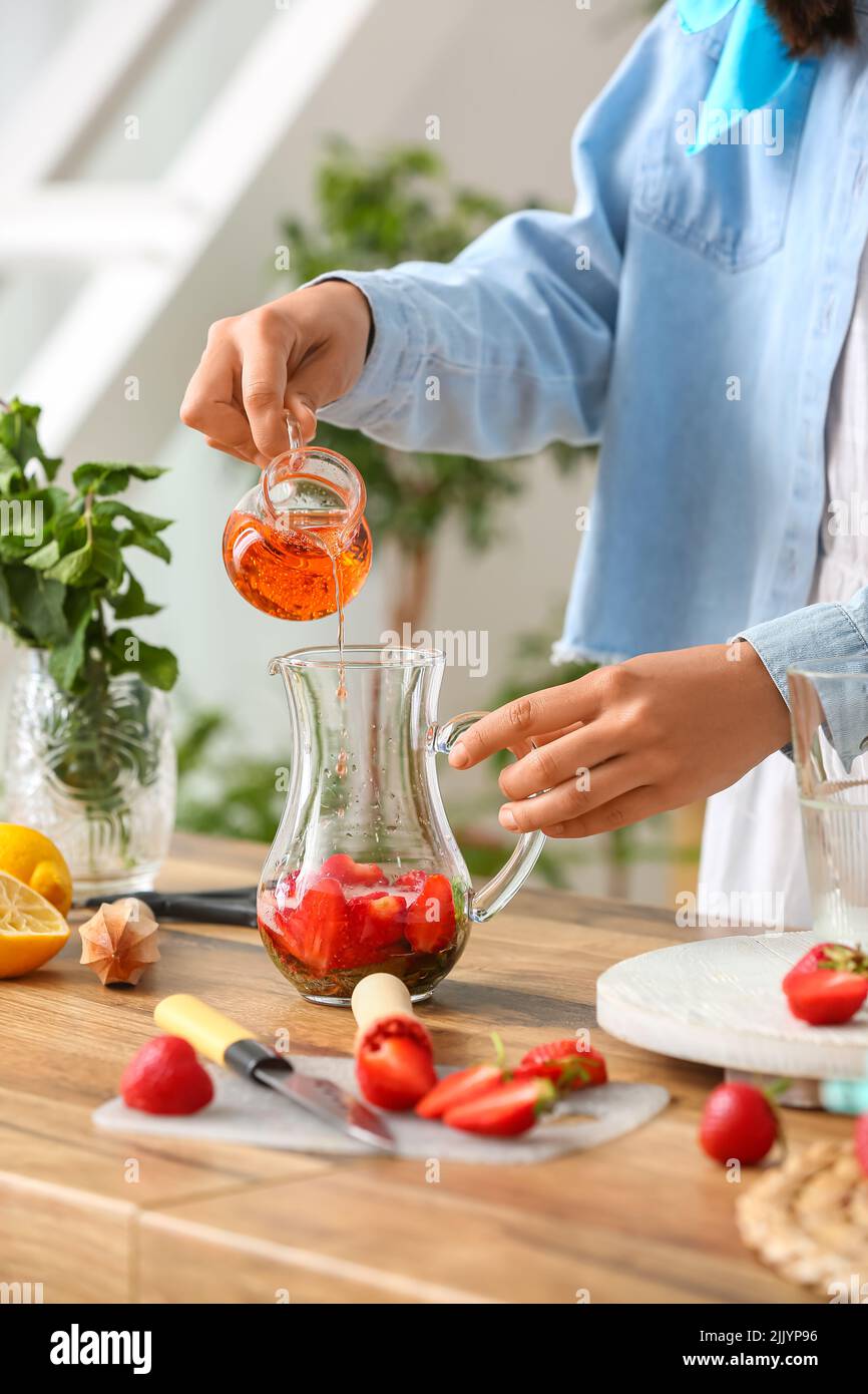 Woman pouring maple syrup into jug for lemonade on wooden table Stock ...