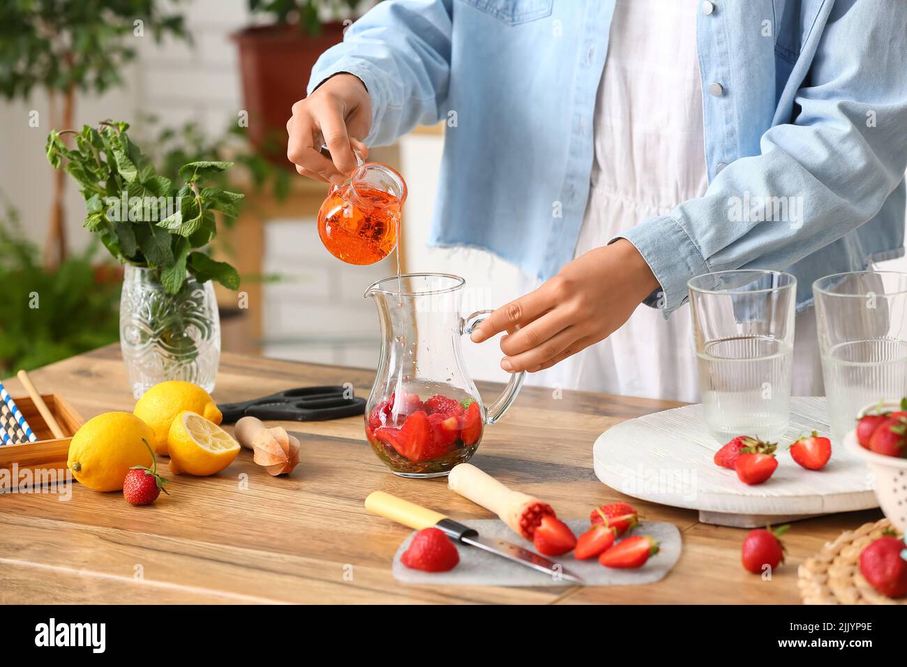 Woman pouring maple syrup into jug for lemonade in kitchen Stock Photo ...