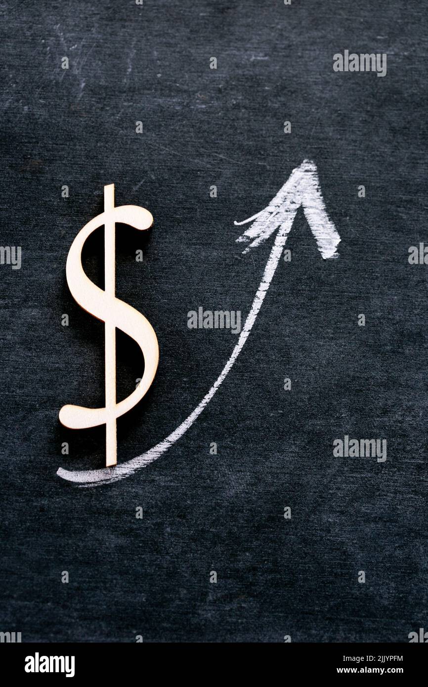 Dollar sign and up arrow on black chalkboard background.Economic ...