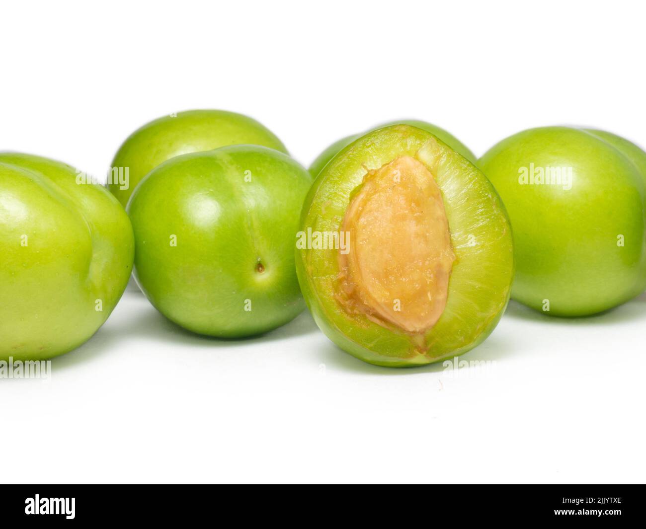 Green cherry plum on a white background. Fruit for making tkemali sauce ...