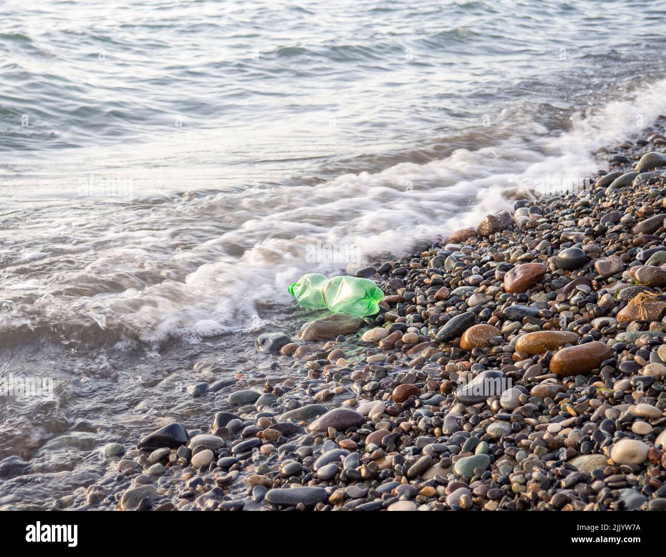 A green plastic bottle washed ashore. Environmental problems. Plastic ...