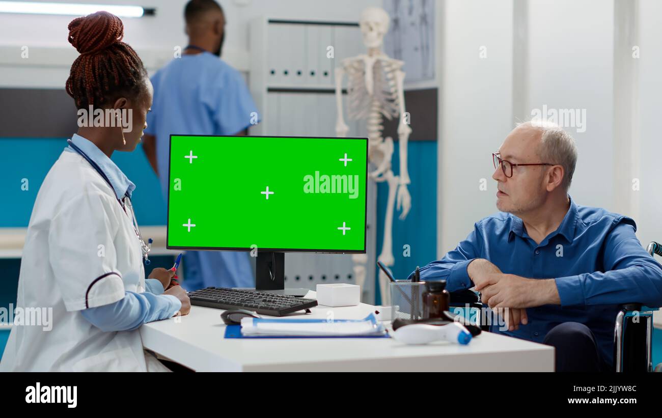 Doctor and patient with impairment using greenscreen on monitor at ...