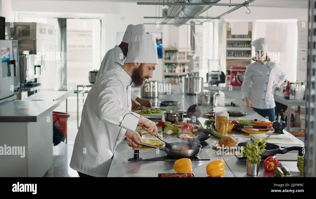 Professional chef adding grated parmesan cheese on food in pan, cooking ...