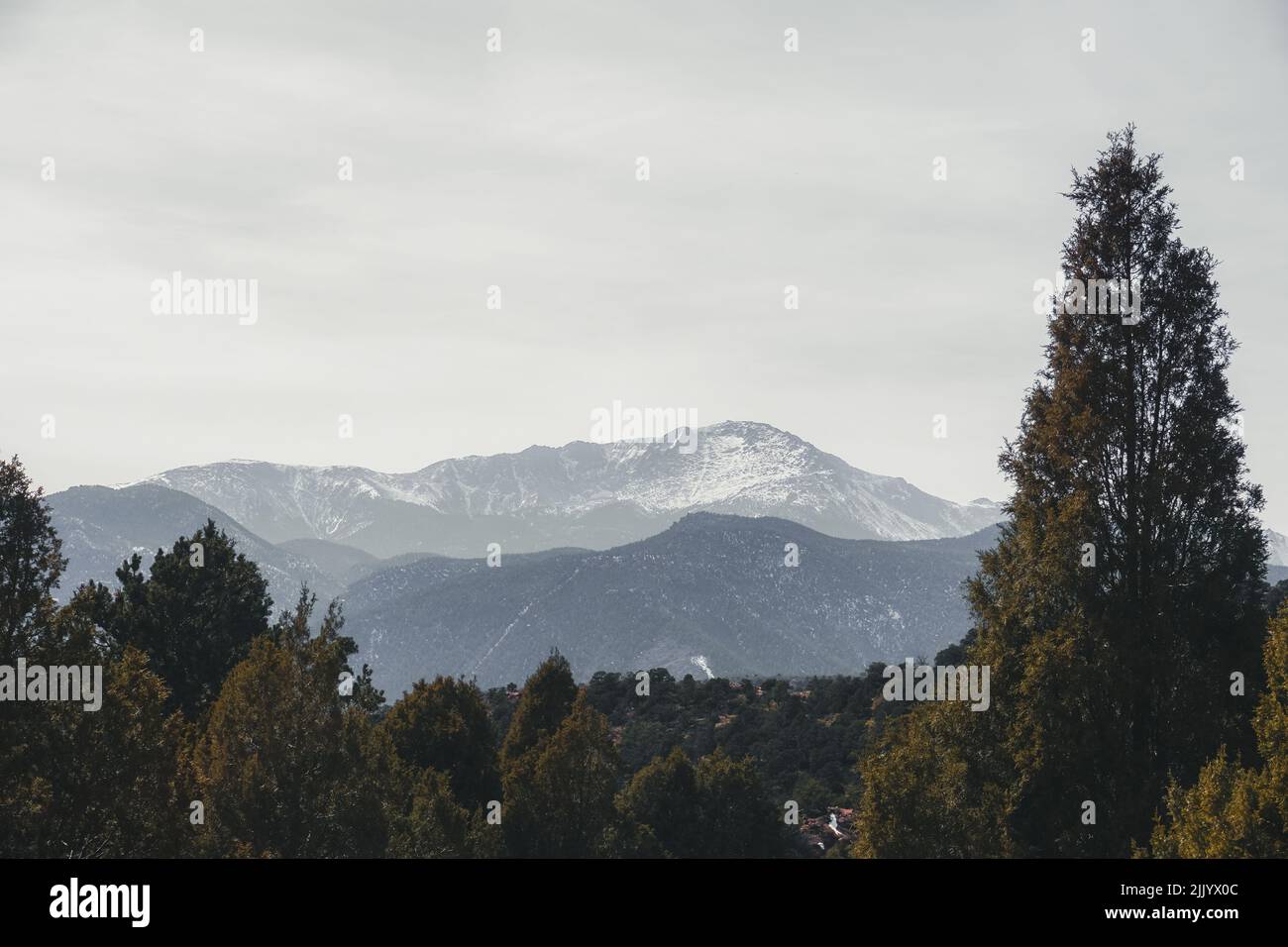 A beautiful view of Pikes Peak Mountain behind green trees Stock Photo ...