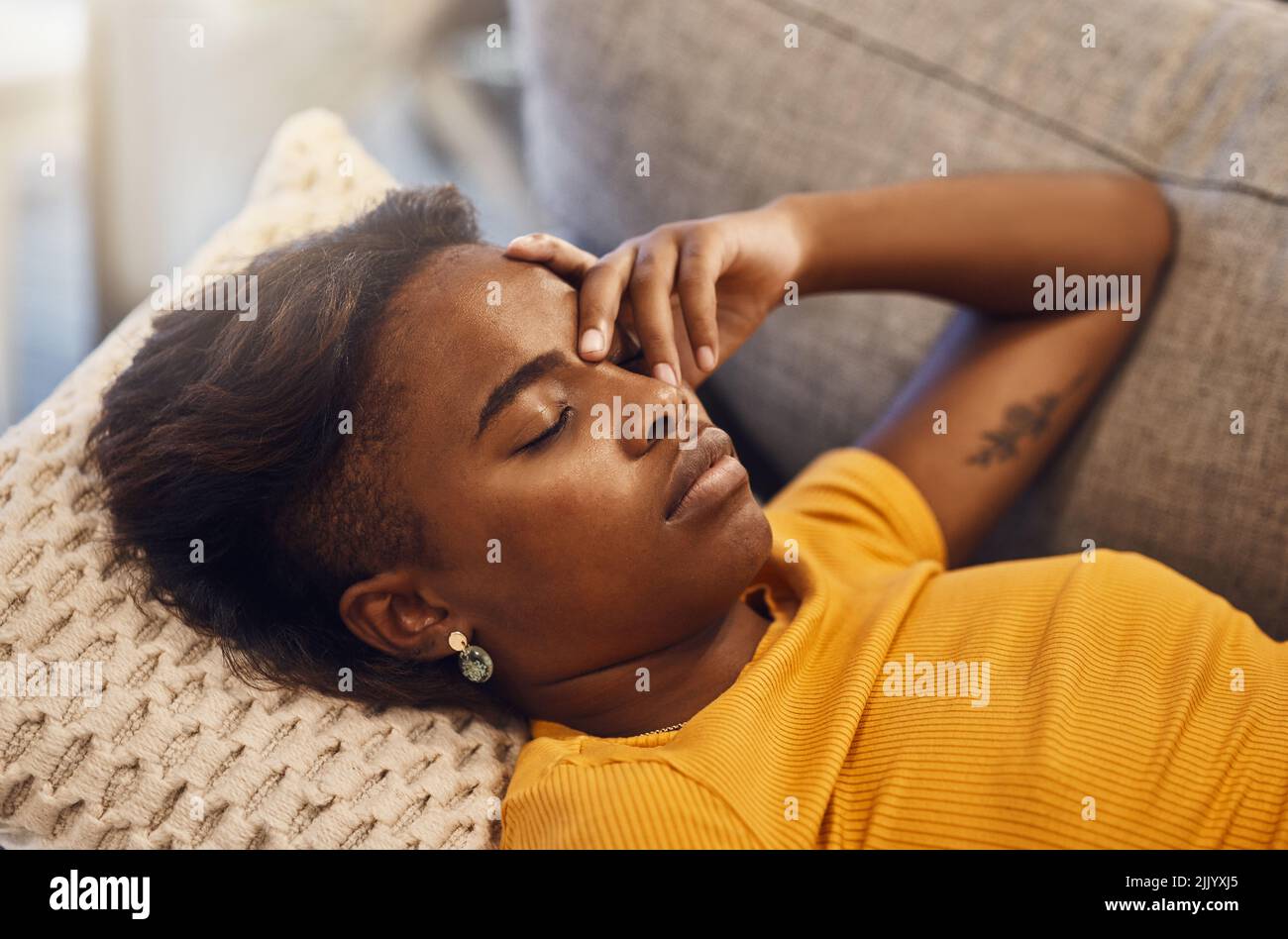 Tired, bored and exhausted female sleeping on a couch at home. African ...
