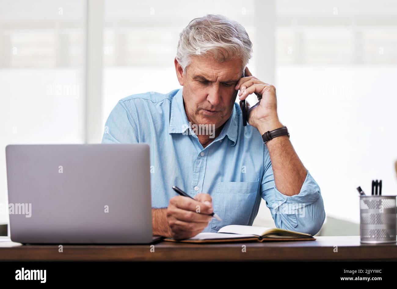 Give me the details... a mature man making notes while talking on his ...