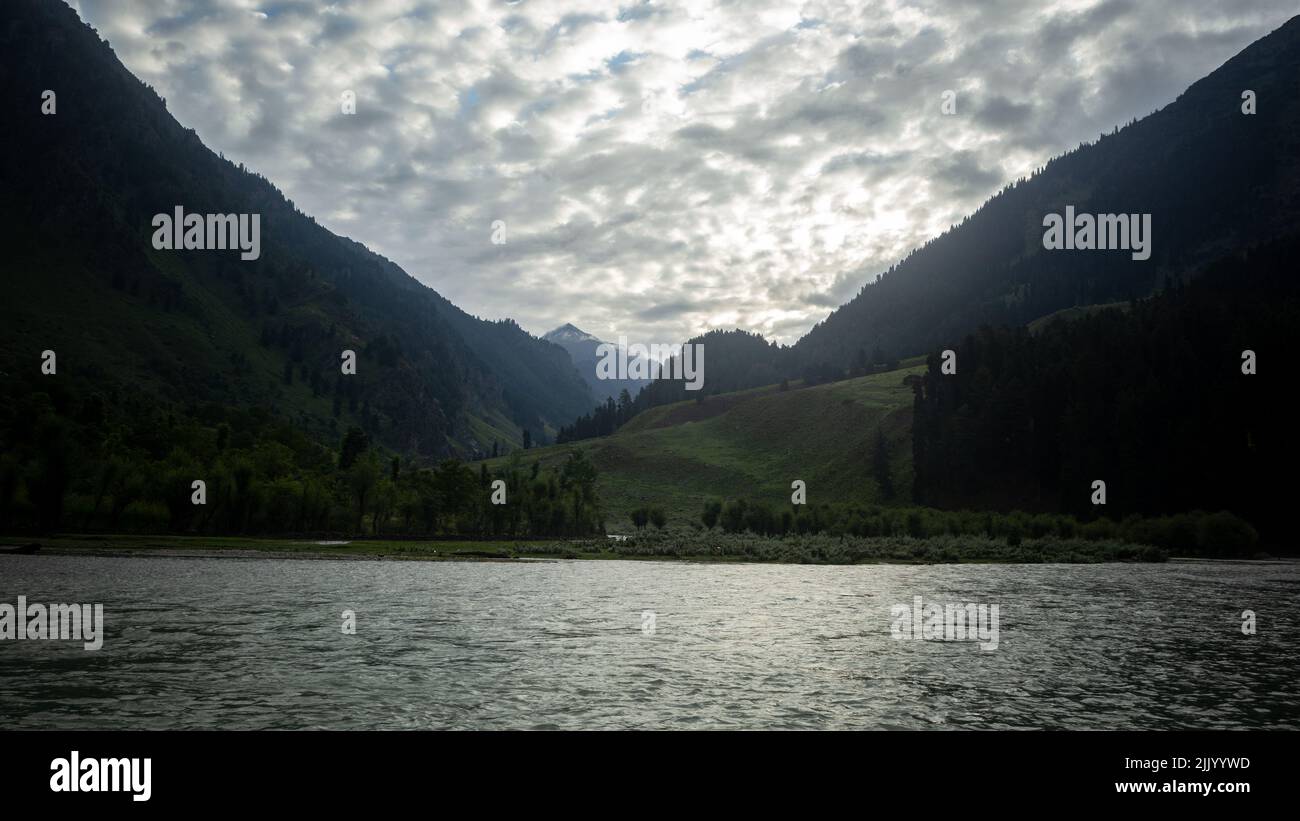 A scenic viw of a calm sea and mountain landscape under a bright cloudy ...