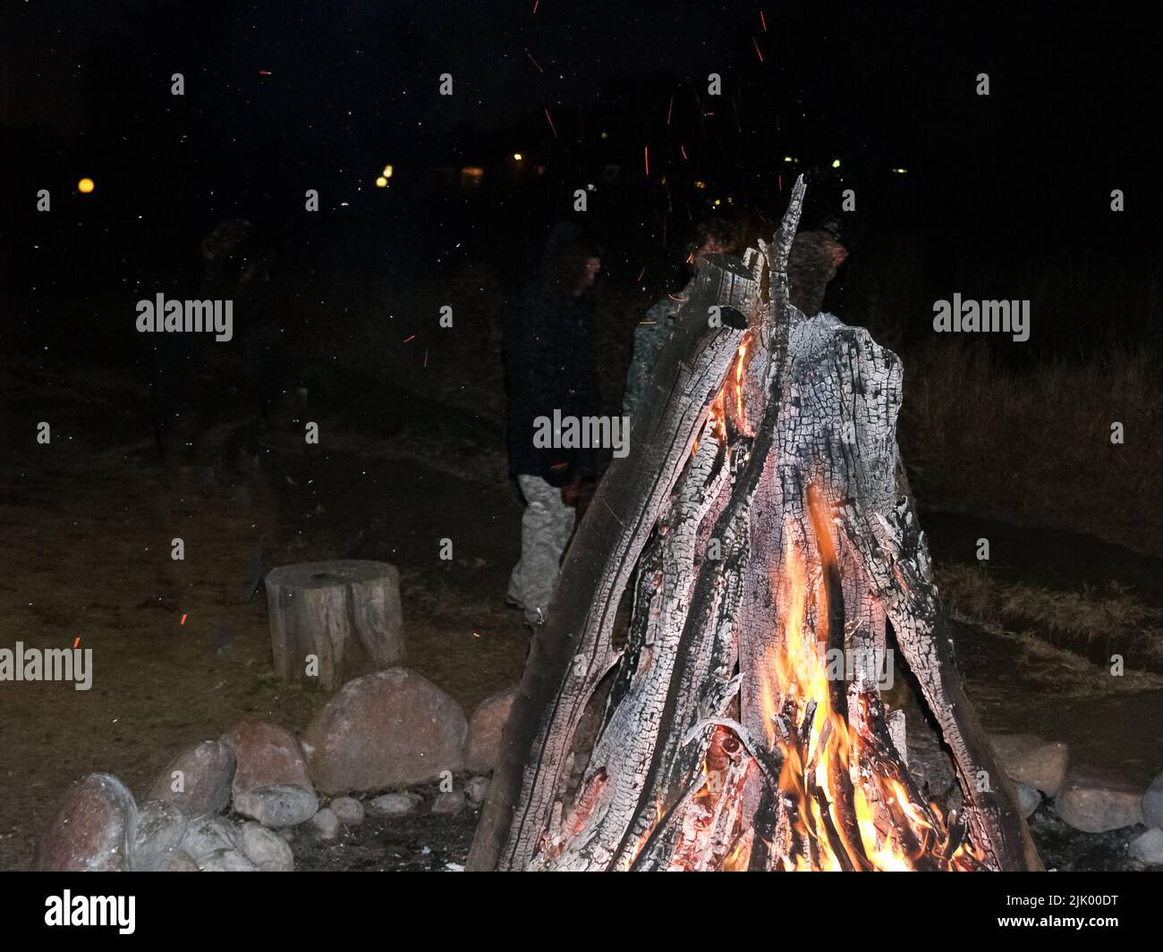 Burning log with hot flames, cracked pattern of charred wood and sparks ...