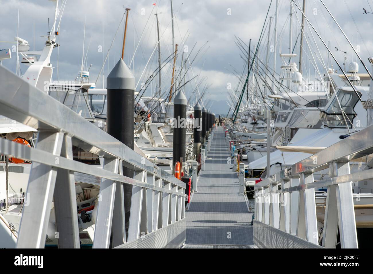 Stainless steel rails of ramp leading down to marina piers and boats in ...