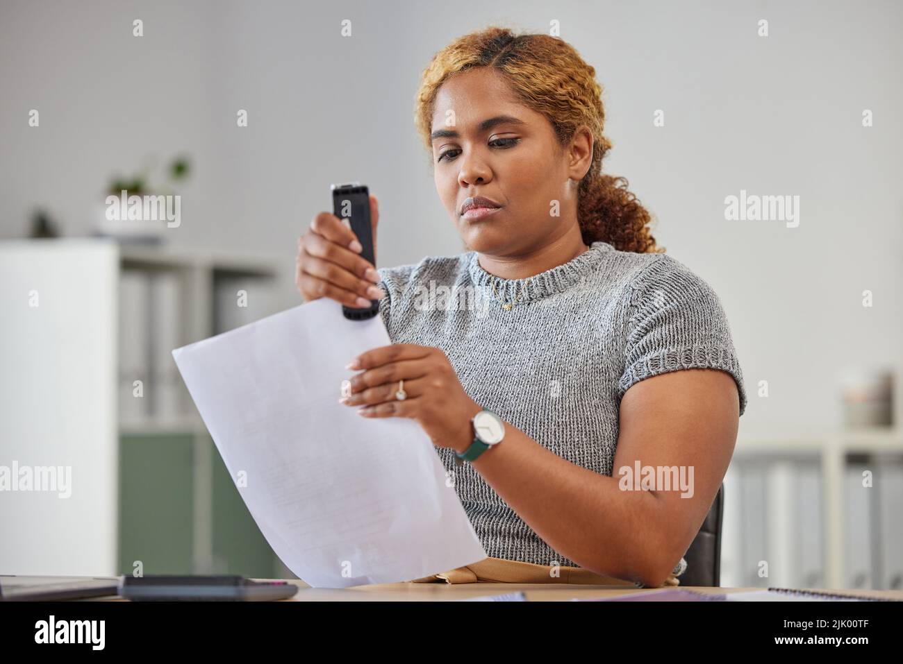Female office worker stapling paper together in her office at work ...
