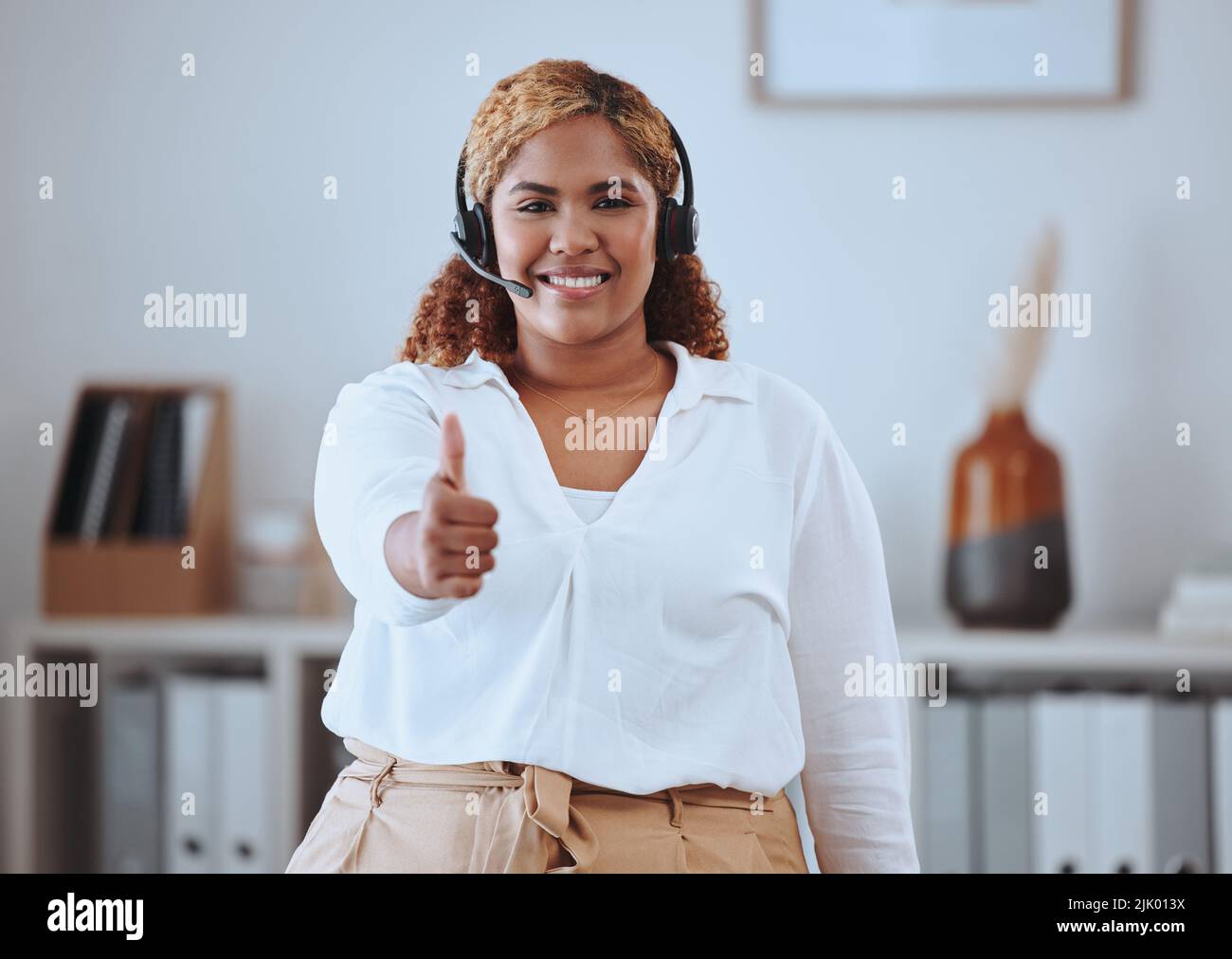 Thumbs up from happy call center agent wearing a headset and smiling in ...