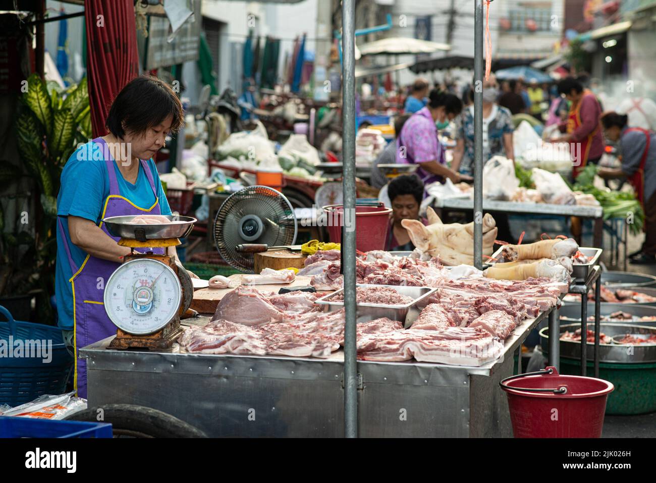 Unidentified Thai vendors selling fresh pork to bring to cook at the morning market. Outdoor ...