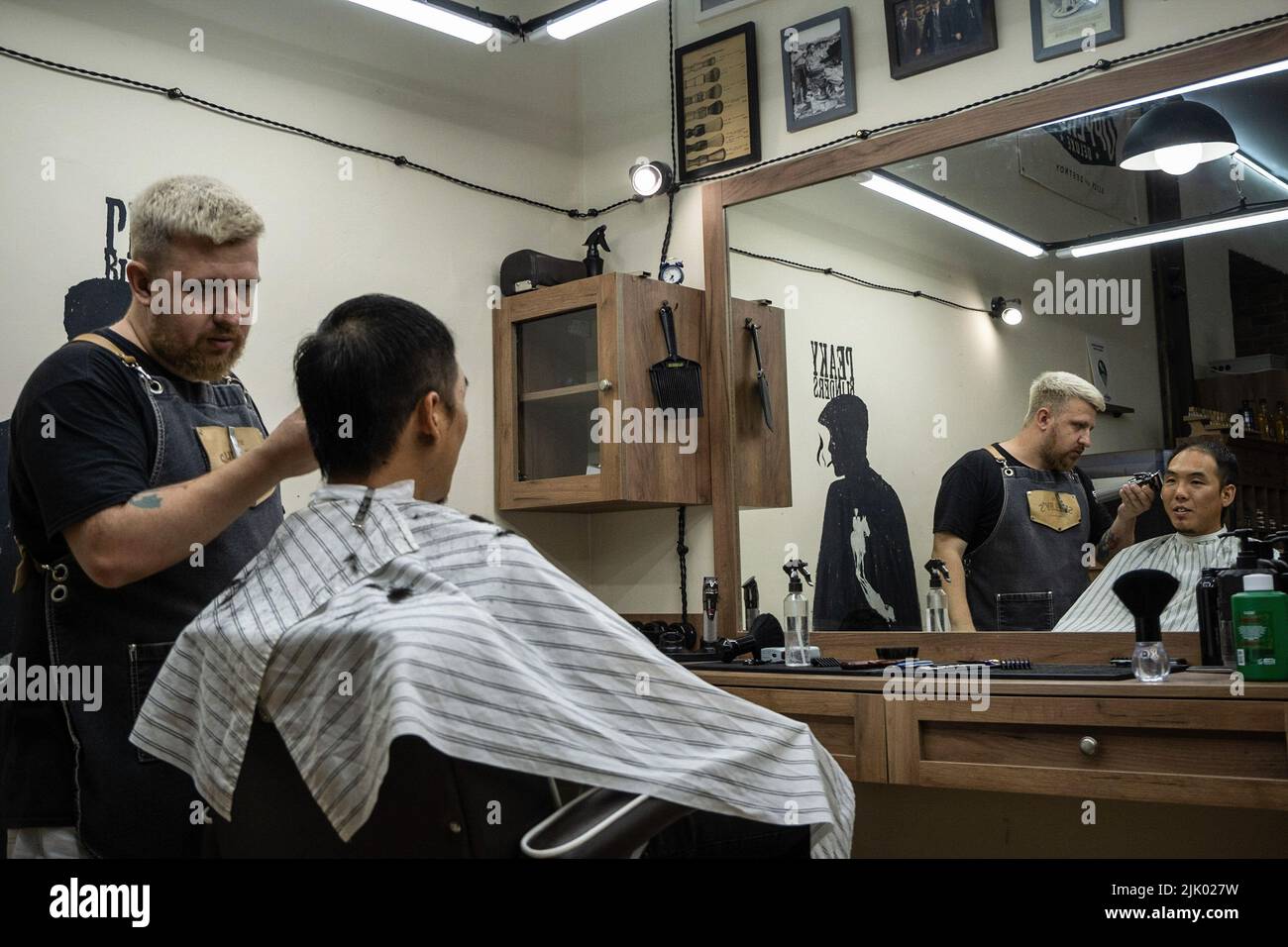 A hairstylist gives a customer a haircut at a re-opened barbershop ...
