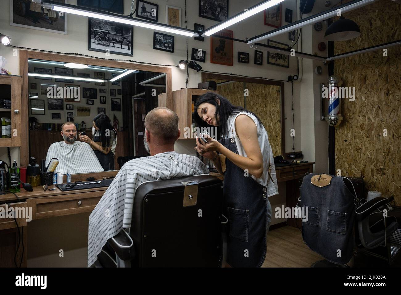 A hairstylist gives a customer a haircut at a re-opened barbershop ...