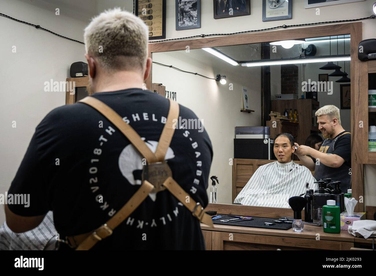 A hairstylist gives a customer a haircut at a re-opened barbershop ...