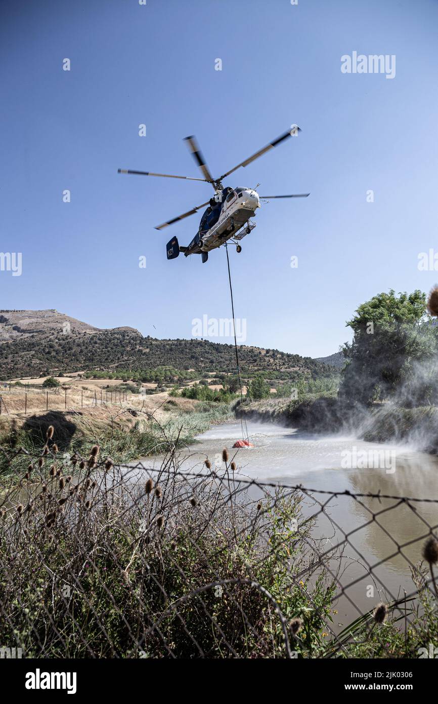 A helicopter picks up water in the town of Contreras. A fire has ...