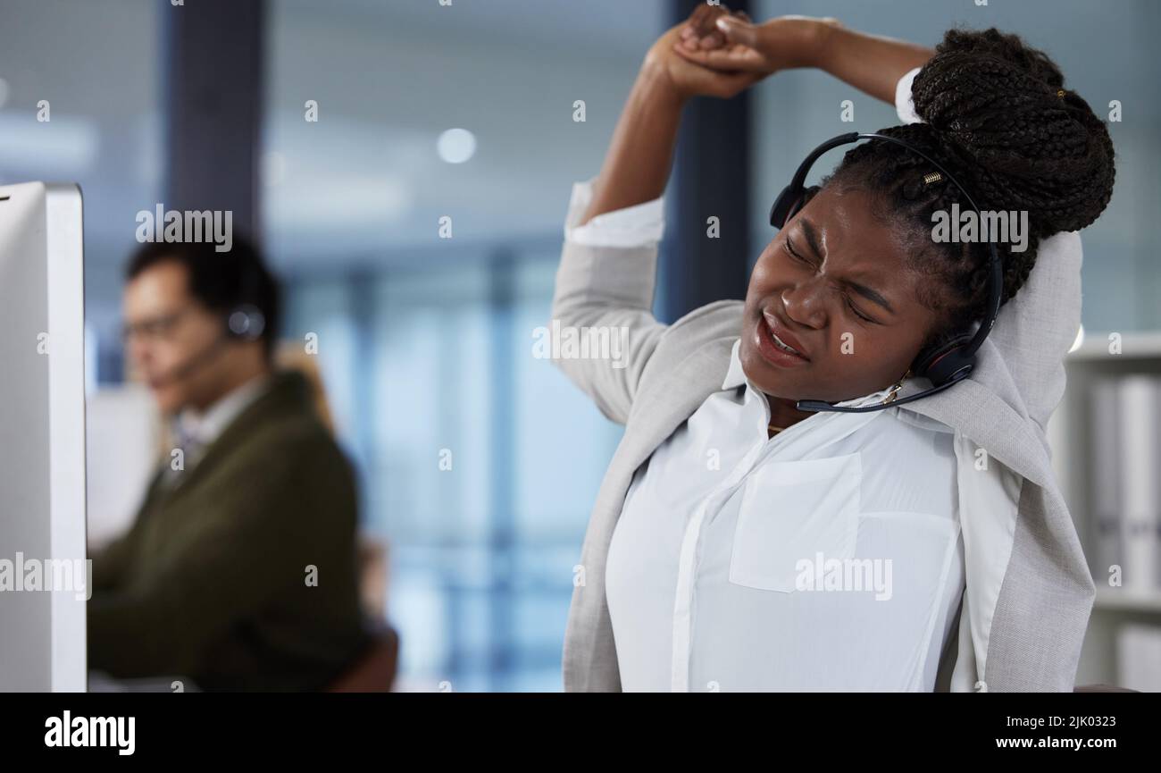 Everyone deserves a break. a young female call center agent stretching ...