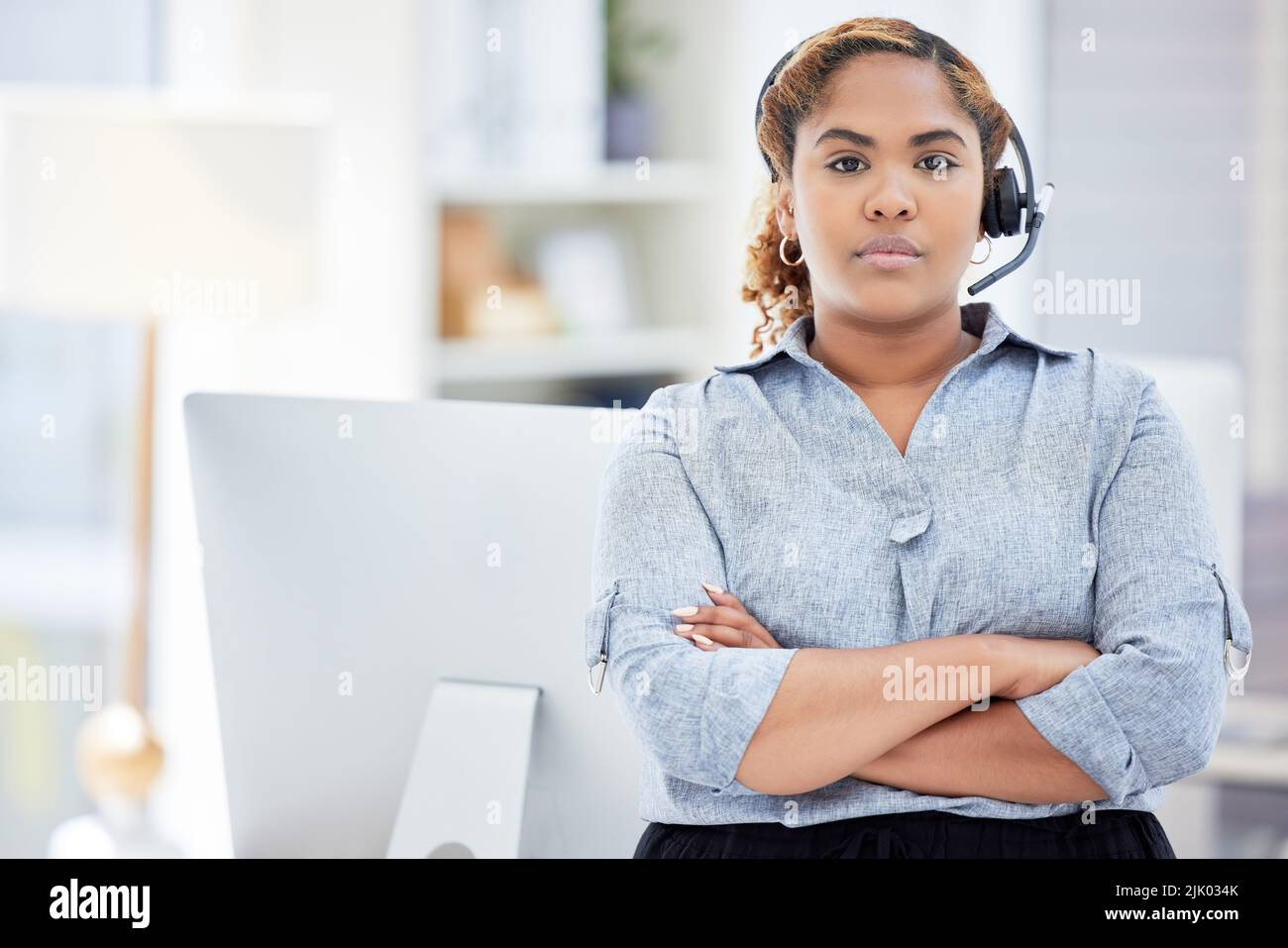 Serious female customer service worker with headphones at the office at ...