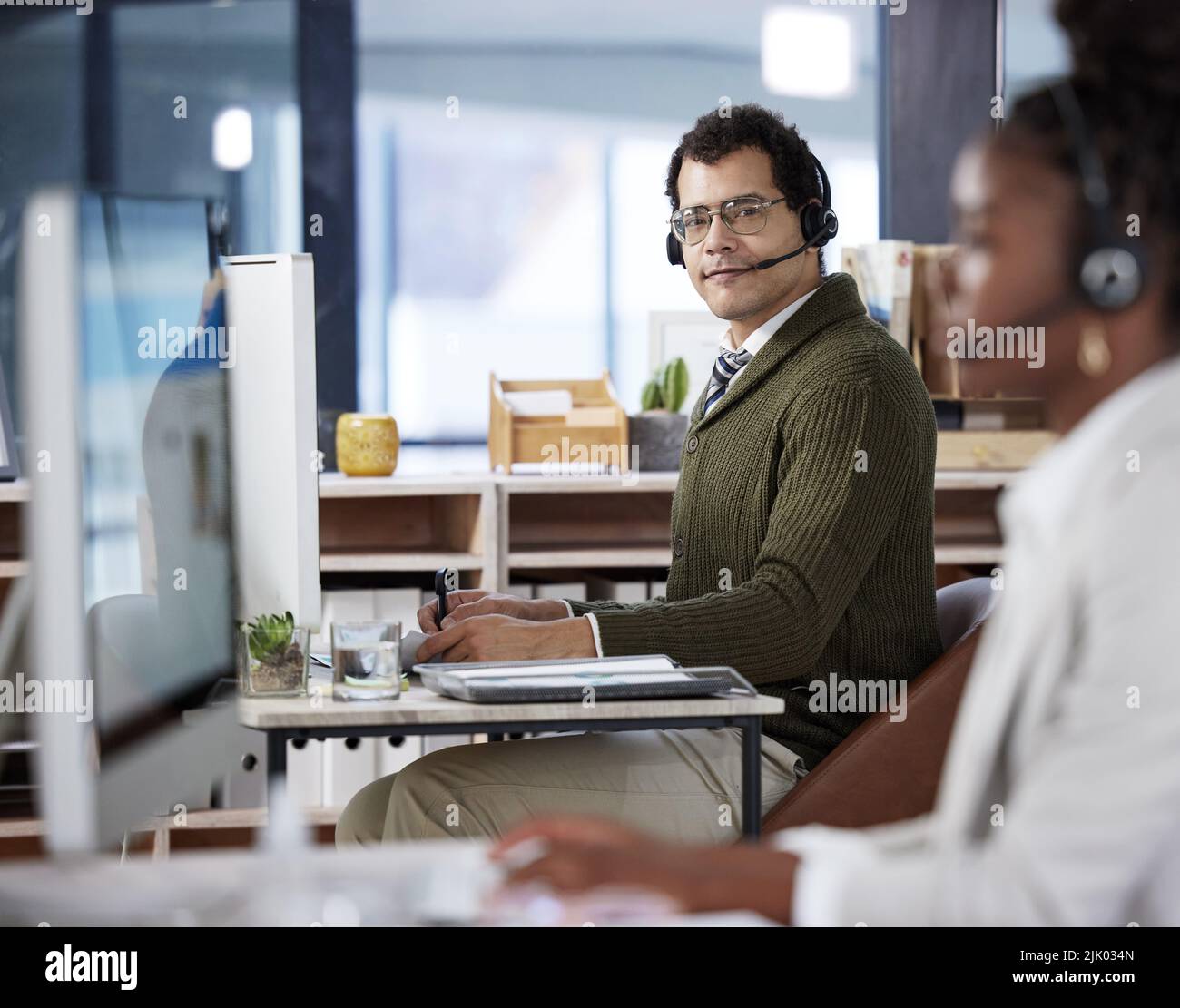 Hes got some work to do. two call center agents working in an office ...